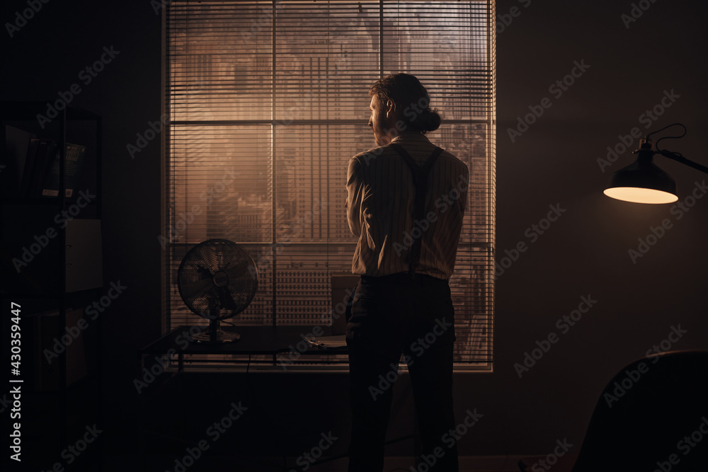 scene of a brutal young detective looking out of a window overlooking ...