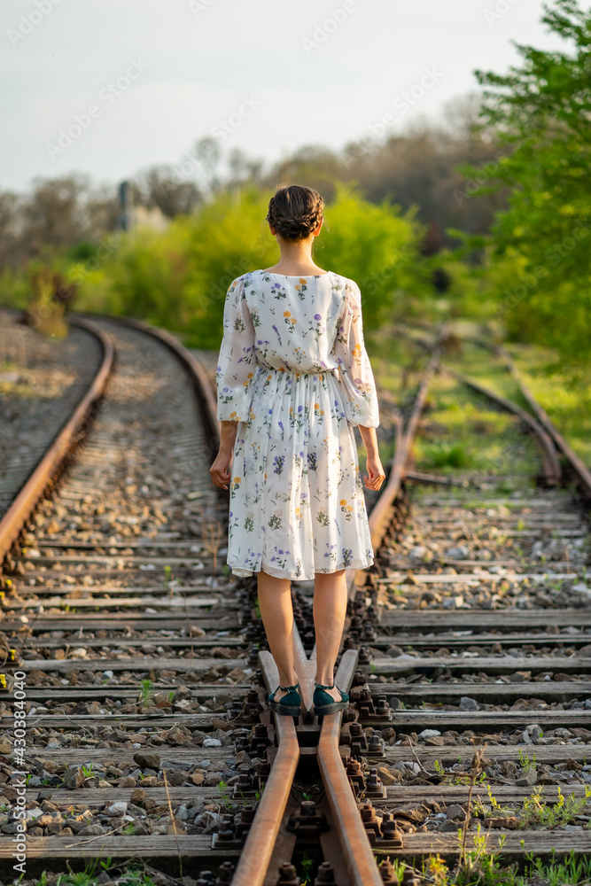 Young and beautiful Caucasian girl walking on a railway that splits in ...