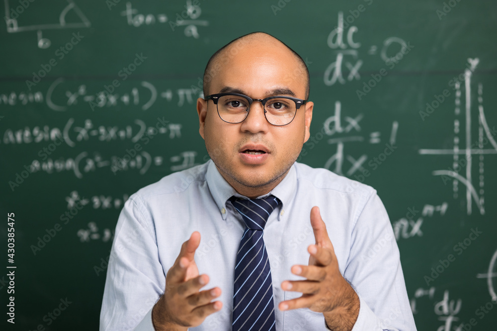 Foto de Indian young teacher man looking at camera sitting teaching ...