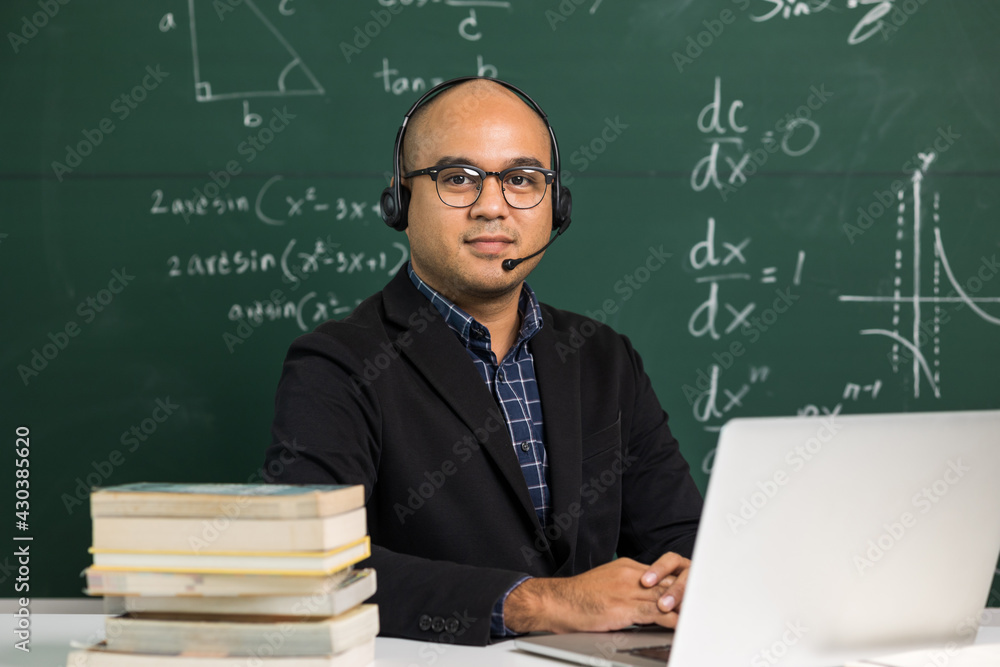 Indian young teacher man looking at camera sitting teaching online ...