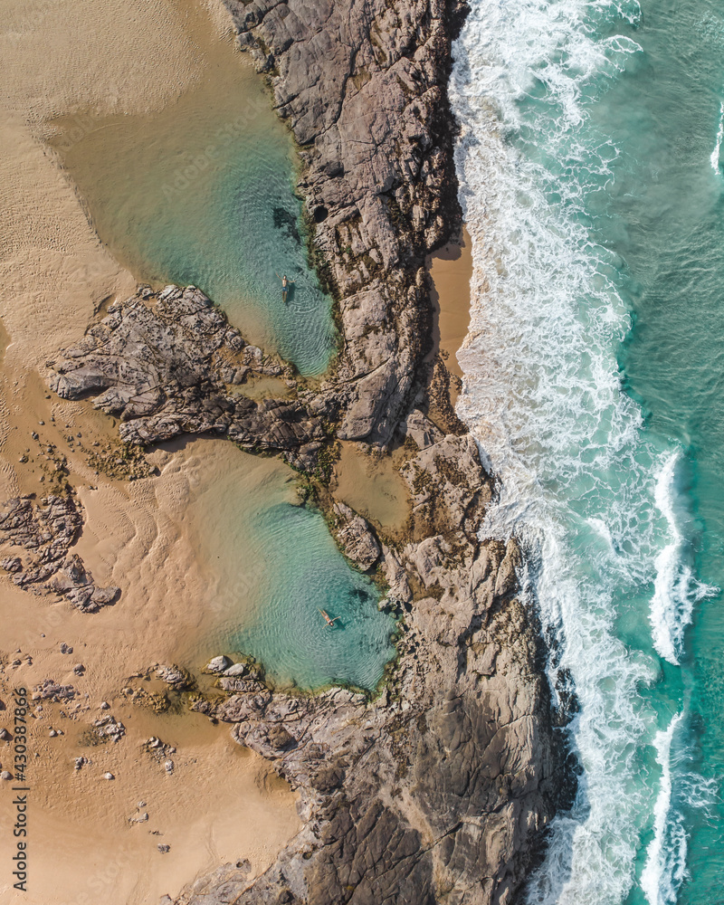 Aerial view of two people floating in separate rock pools at the ...