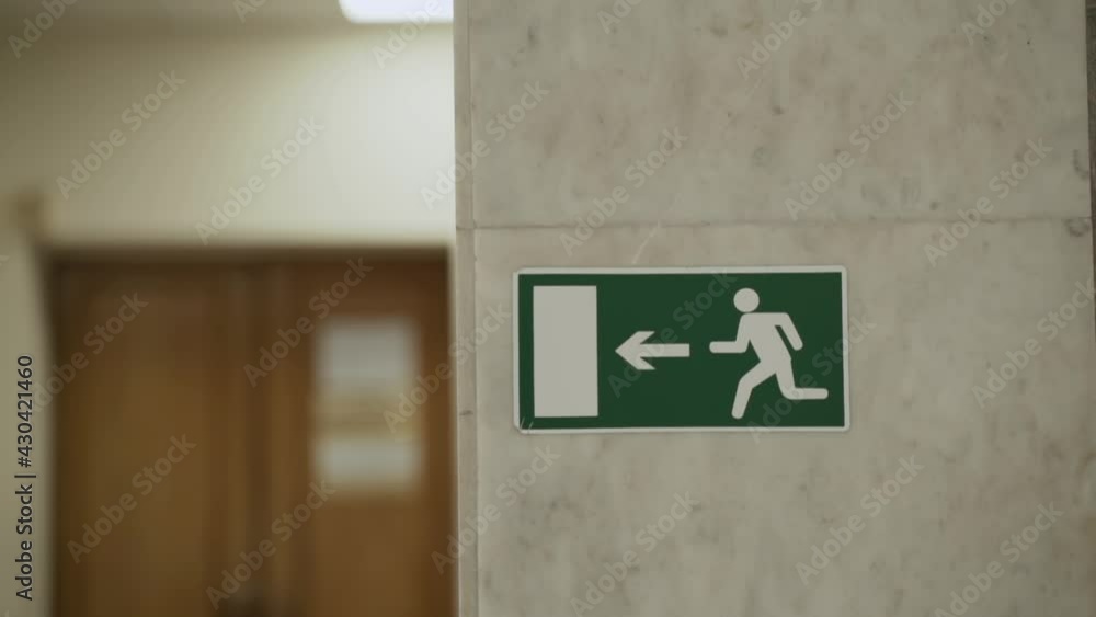 Green sign indicating direction of the emergency exit is attached to ...