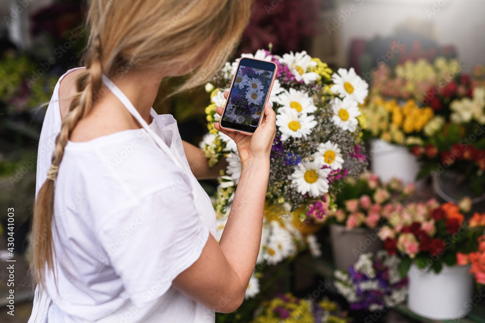 Woman florist is taking photo of wildflowers bouquet for a client in ...