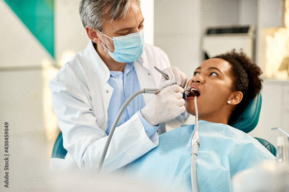 African American woman having dental polishing procedure at dentist's ...