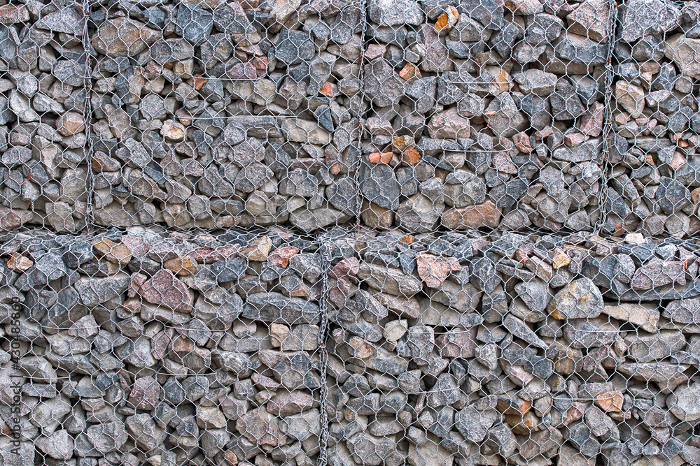 Stones and gravels in wire mesh background. Rockfall protection barrier ...