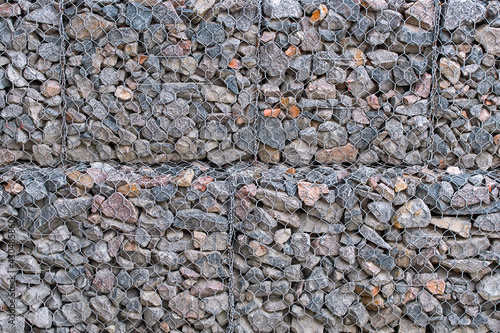 Stones and gravels in wire mesh background. Rockfall protection barrier ...