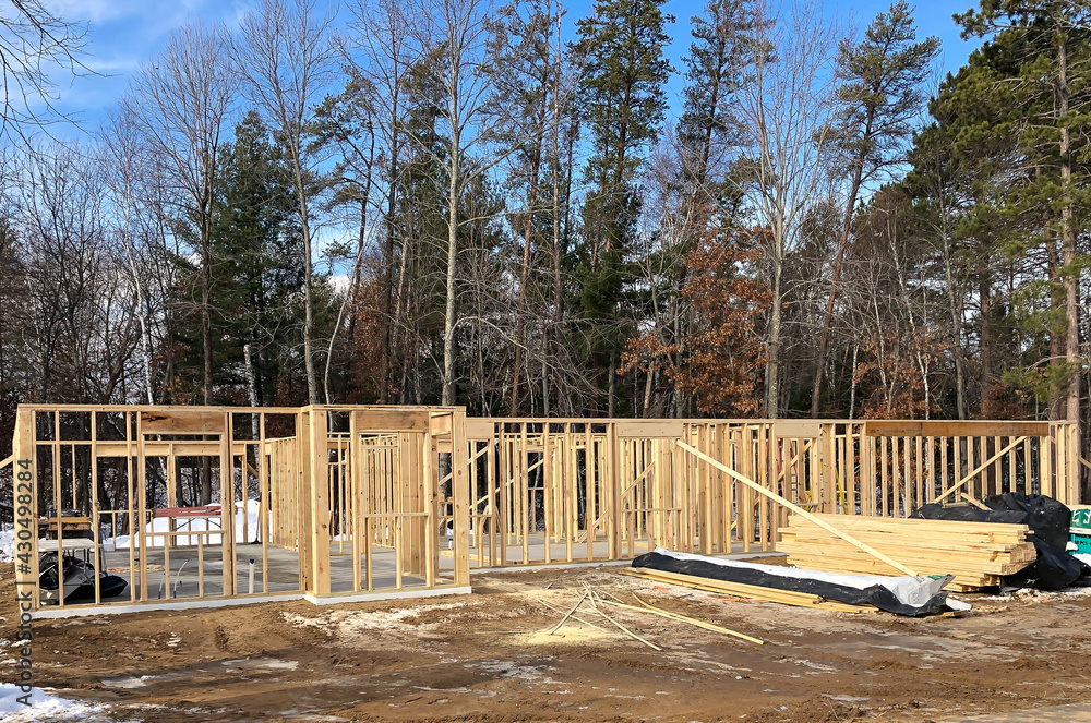 House construction site with wall studs and stacks of wood lumber ...
