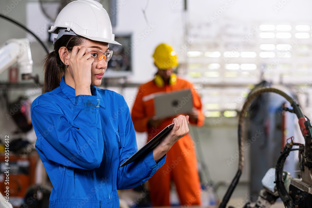 Engineer woman use tablet to control welding robotic automatic arm ...
