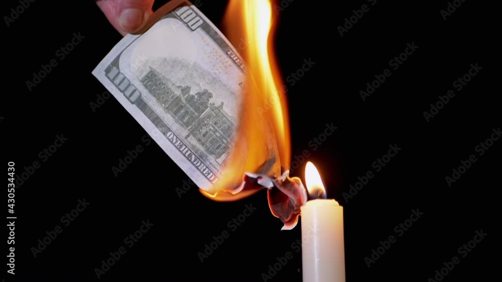 Burning 100 Dollar Bill over a Candle flame on a Black Background ...