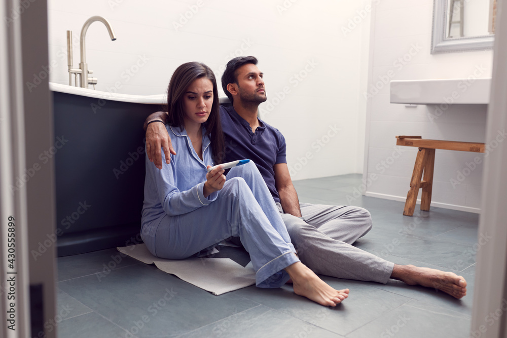 Foto de Disappointed Couple Sitting On Floor In Bathroom At Home With ...