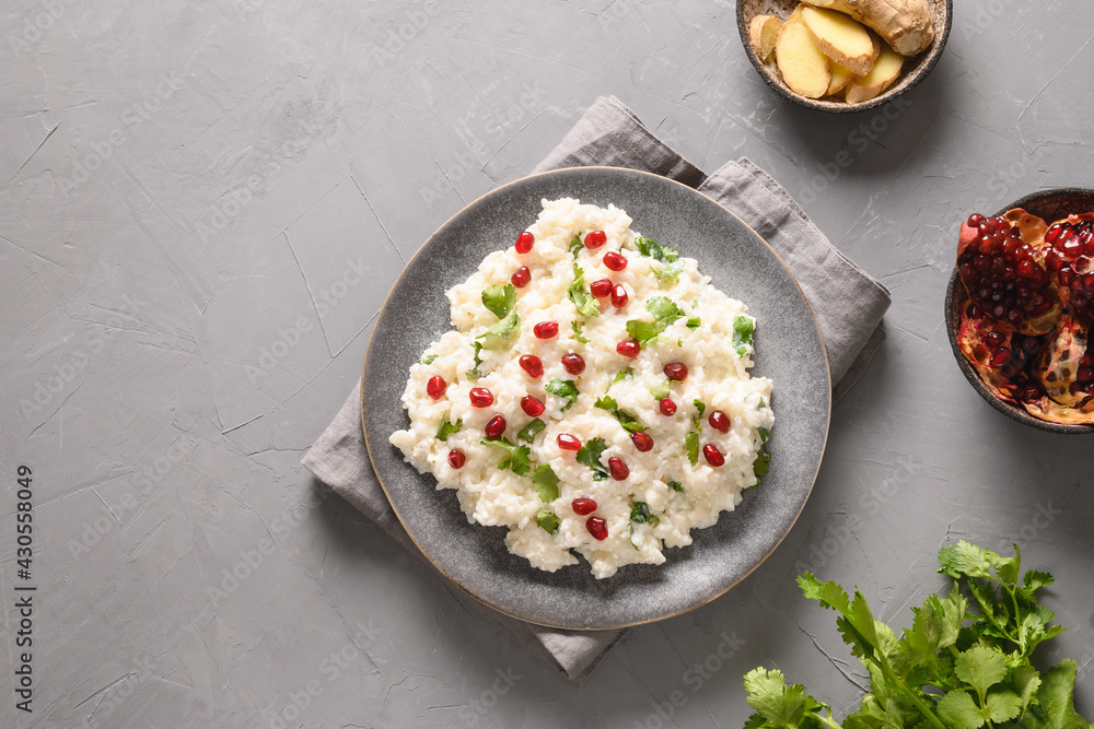 Curd Rice with pomegranate, cilantro, ginger on a grey background. Top ...