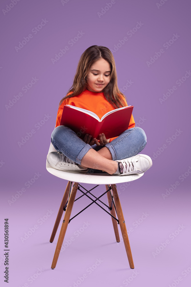Girl reading book on chair Stock Photo | Adobe Stock