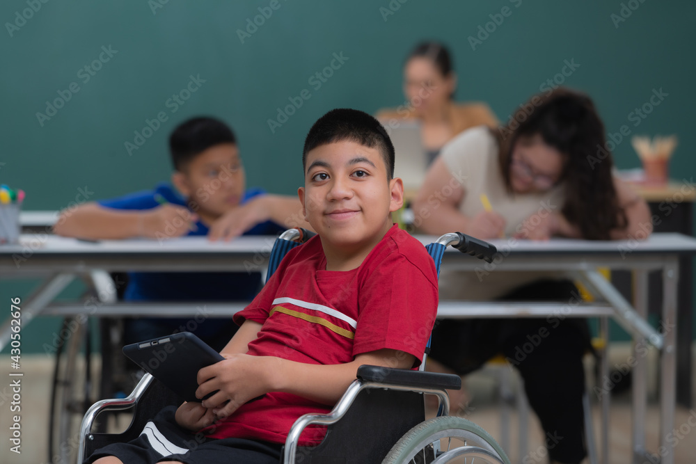 Portrait of young handicapped kid boy sitting on wheelchair and looking ...