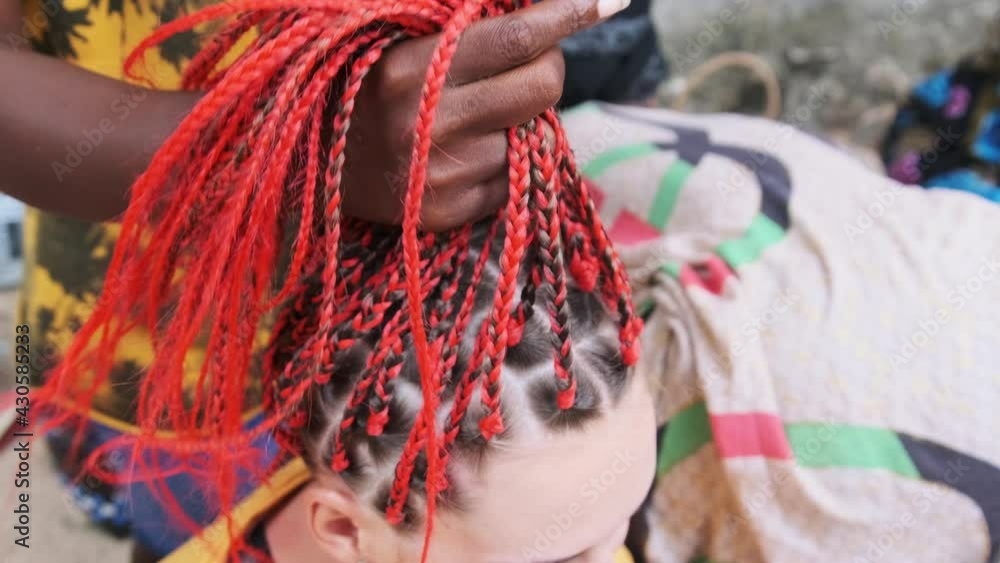 The process of weaving African braids with red kanekalon. Black African ...