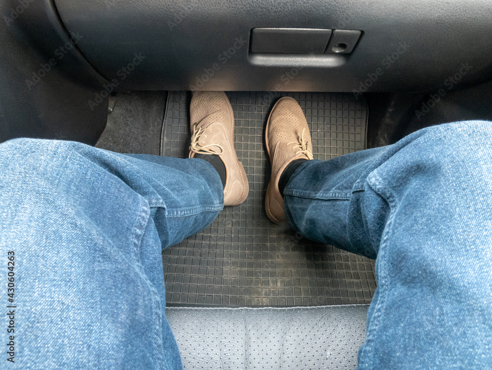 The passenger is sitting in the passenger seat of the car. The legs of ...