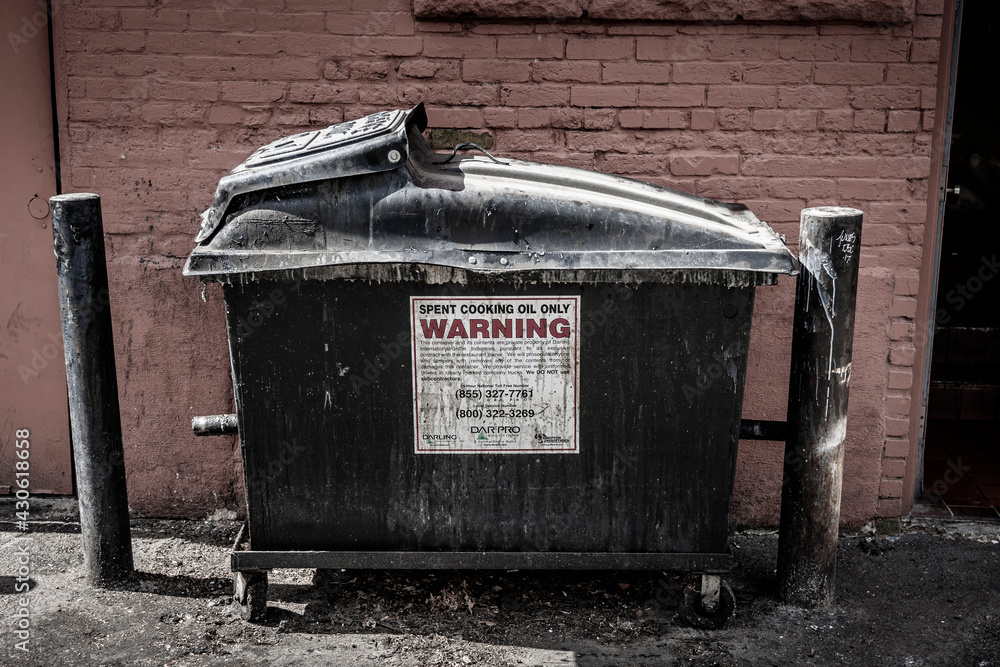 A dirty trash bin is a receptacle for used cooking oil outside a ...