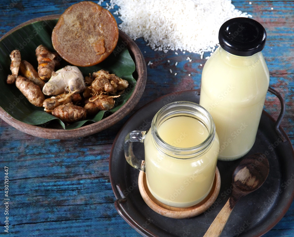 A glass of jamu beras kencur or Indonesian traditional herbal drink ...