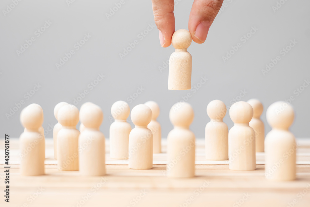 Businessman hand pulling leader man wooden from crowd of employees ...