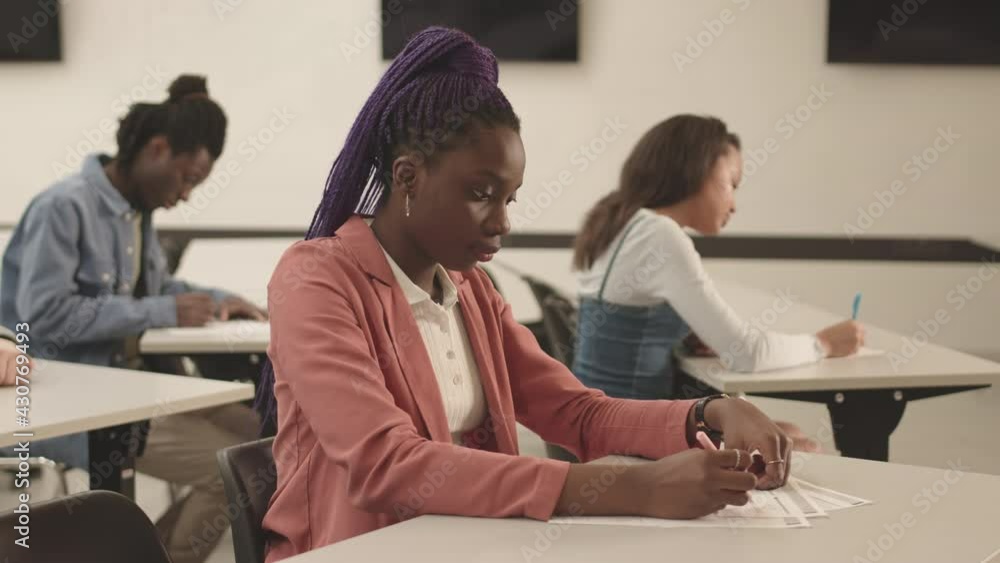 Waist-up of female African college student having exam in classroom ...
