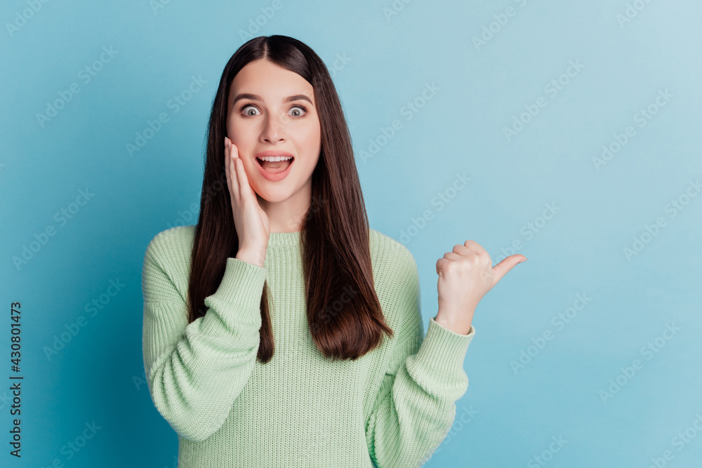 Portrait of a crazy shocked girl pointing thumb away empty space open ...