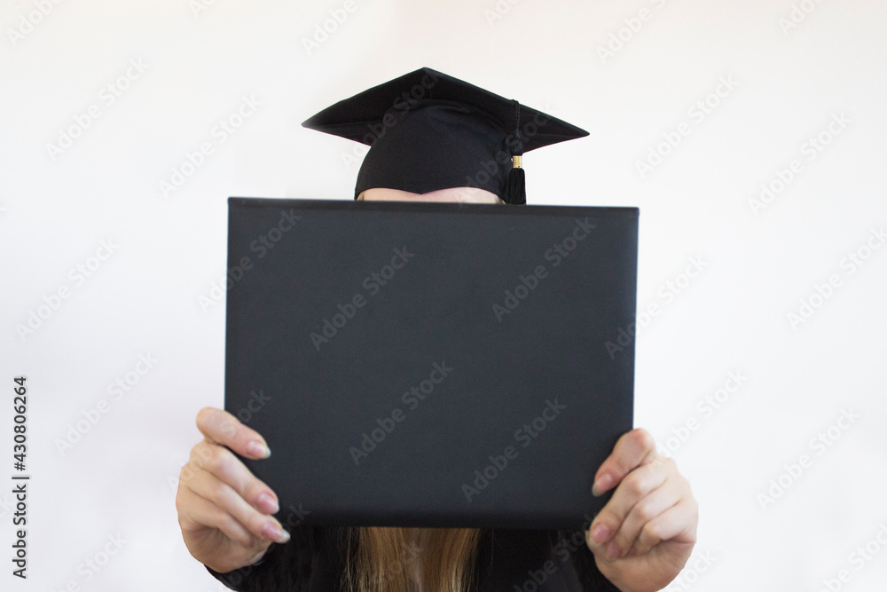 Graduating student holding up a diploma and wearing a graduation cap ...