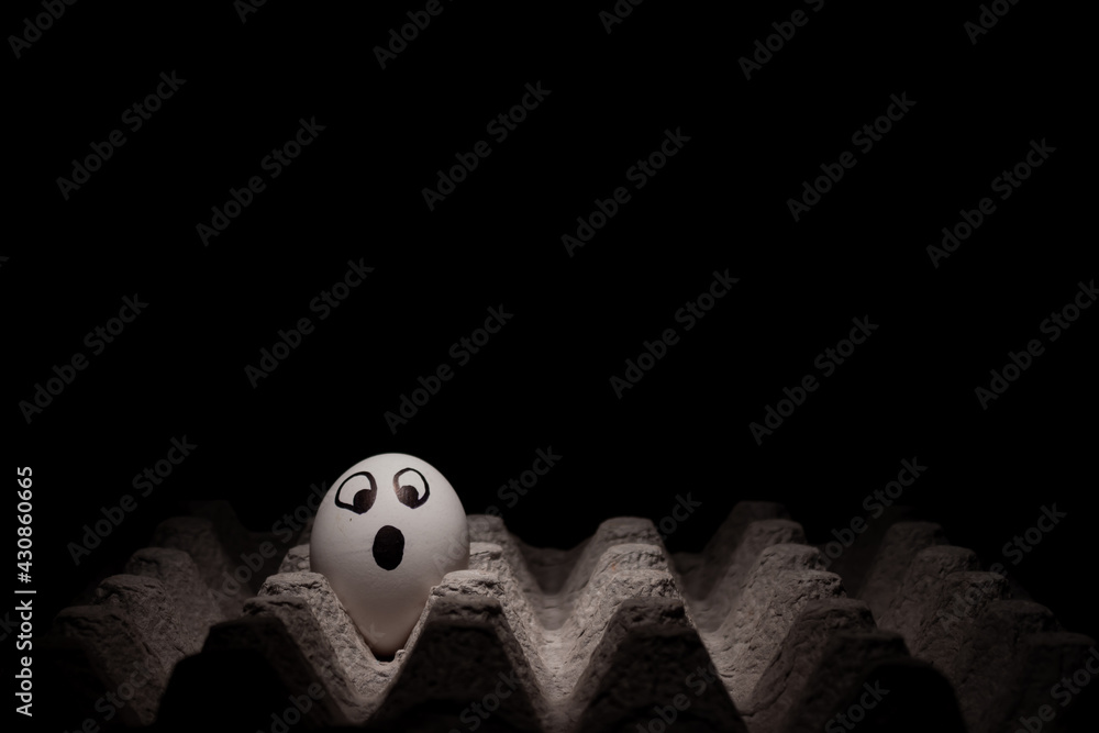 Egg with a scared face in its cardboard box. Black background. Free ...