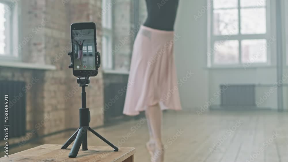 Young talented ballerina using timer on smartphone and tripod for ...