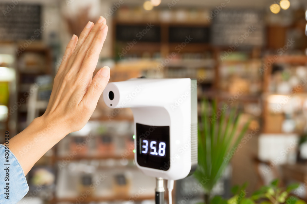 A woman customer raised her hand in front of a digital thermometer with ...