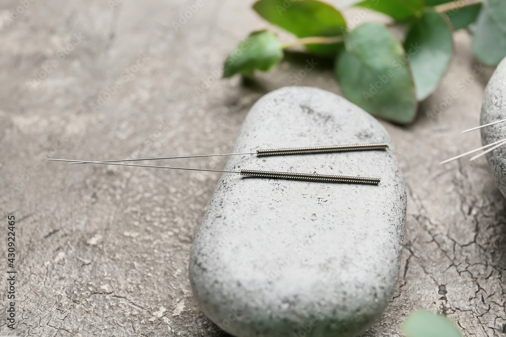 Acupuncture needles and spa stone on grey background Stock Photo ...