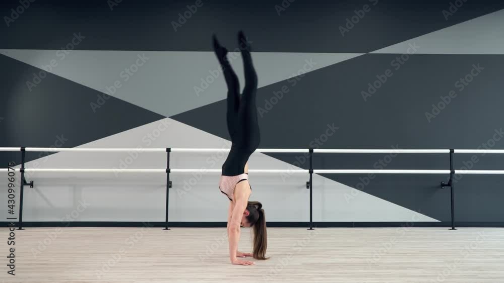 Motion of strong fit woman in tight sportswear standing on arms and ...