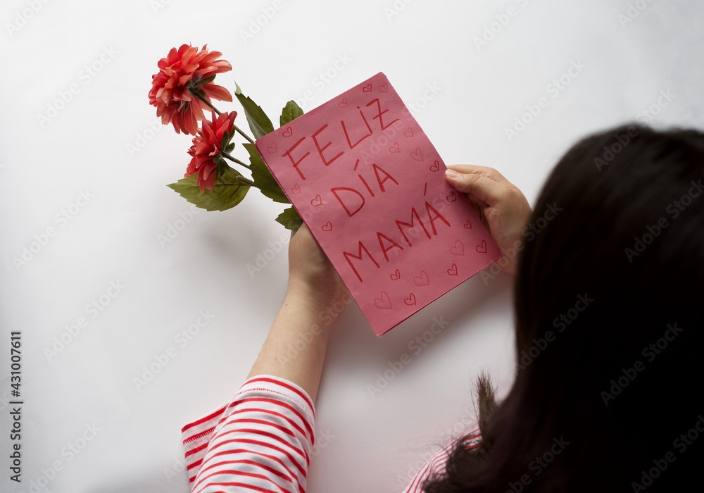 Mom holding flowers and handmade greeting card. Message in Spanish ...