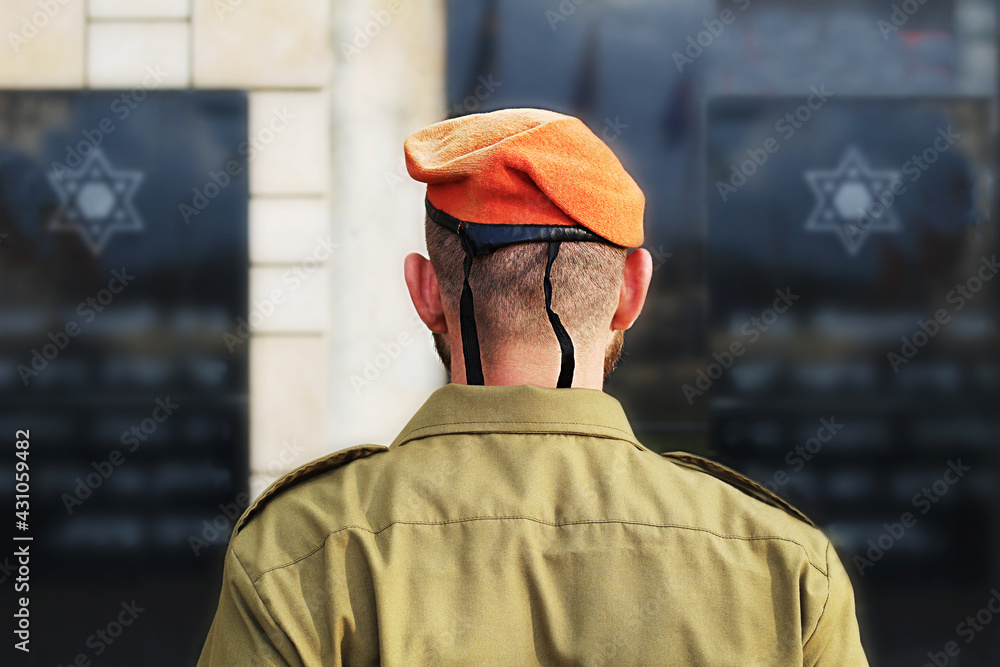 Israeli soldier in front of blurred monuments with Jewish stars at the ...