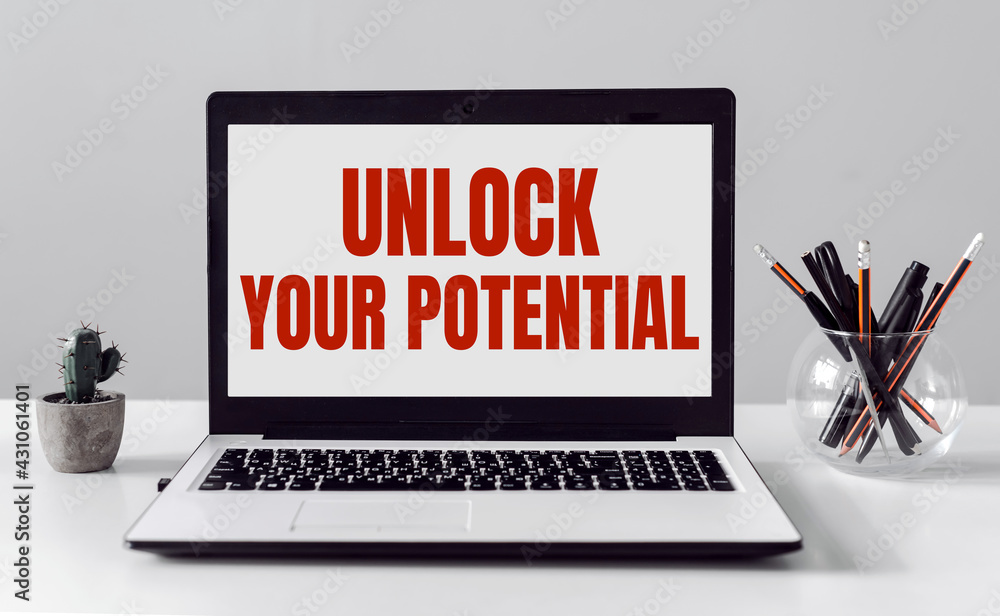 Laptop with UNLOCK YOUR POTENTIAL text on modern office background ...