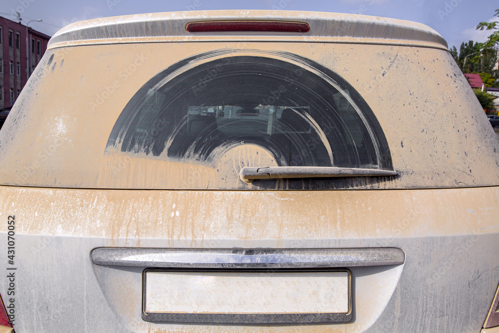 rear window of dirty car covered with layer of dry dust on trunk lid of ...