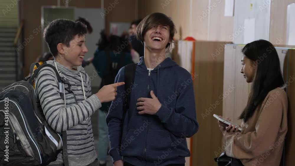 Laughing caucasian bullies scoffing asian schoolgirl standing with ...