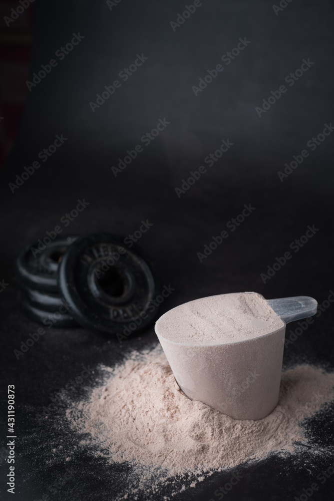 Measured scoop of whey protein powder on dark background with weight ...