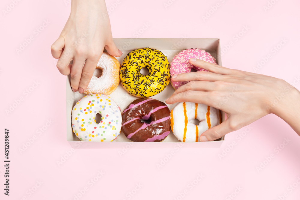 Hands is taking colored glazed donuts in donut box. Hands is grabbing ...