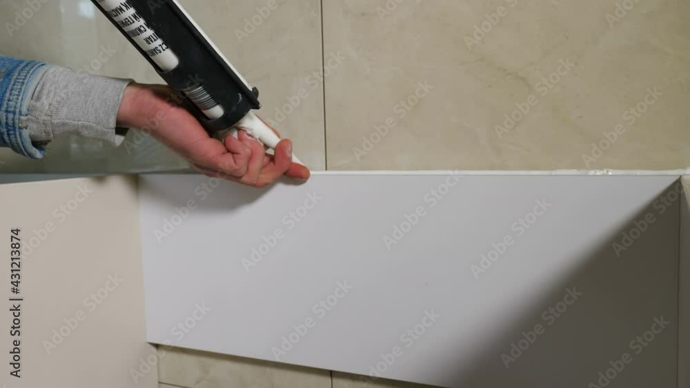 Skilled repairman applying silicone sealant with caulking gun. Male ...