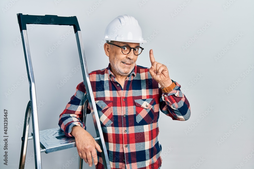 Handsome mature handyman close to construction stairs wearing hardhat ...