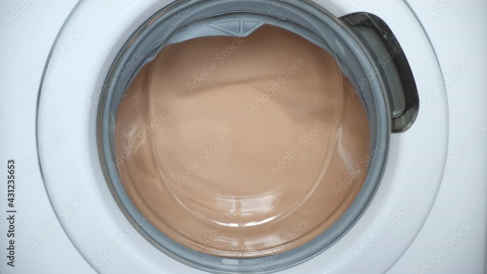 Washing machine wrings out the laundry beige bed linen, closeup window ...