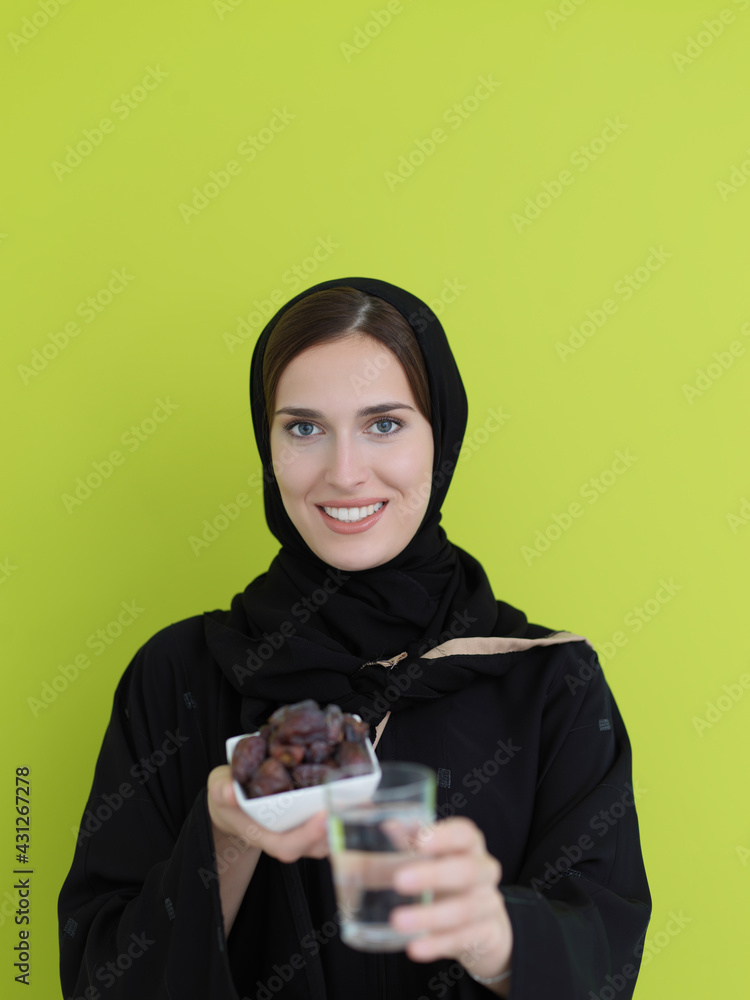 Modern muslim woman in abaya holding a date fruit and glass of water in ...