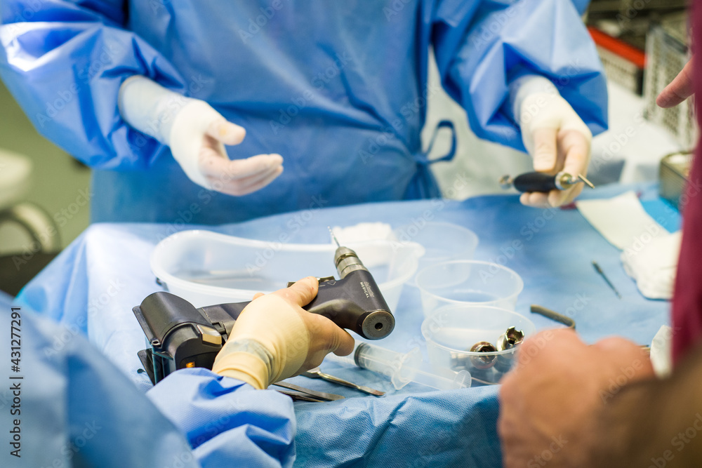 A surgeon and nurse arrange steel surgical instruments during an ...