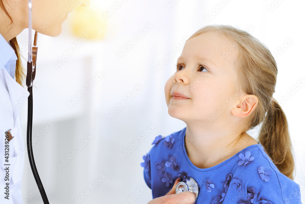 Doctor examining a little girl by stethoscope. Happy smiling child ...