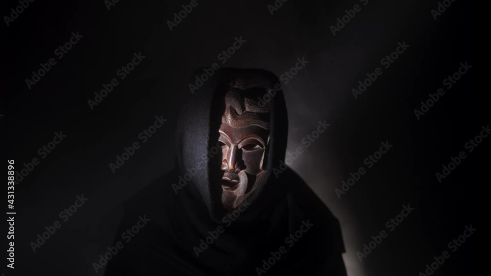 Creepy, masked cultist standing in a dark room. Scary horror scene ...