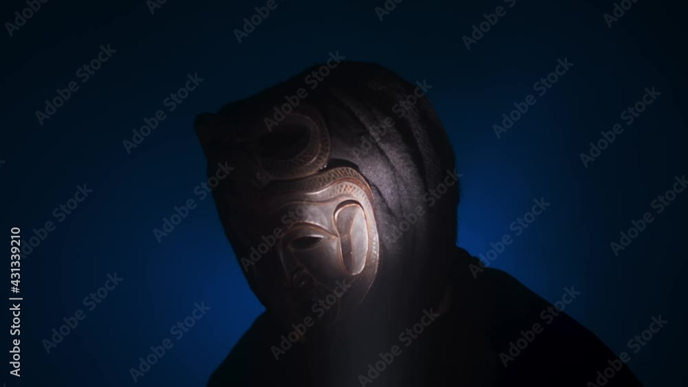 Creepy, masked cultist standing in a dark room. Scary horror scene ...