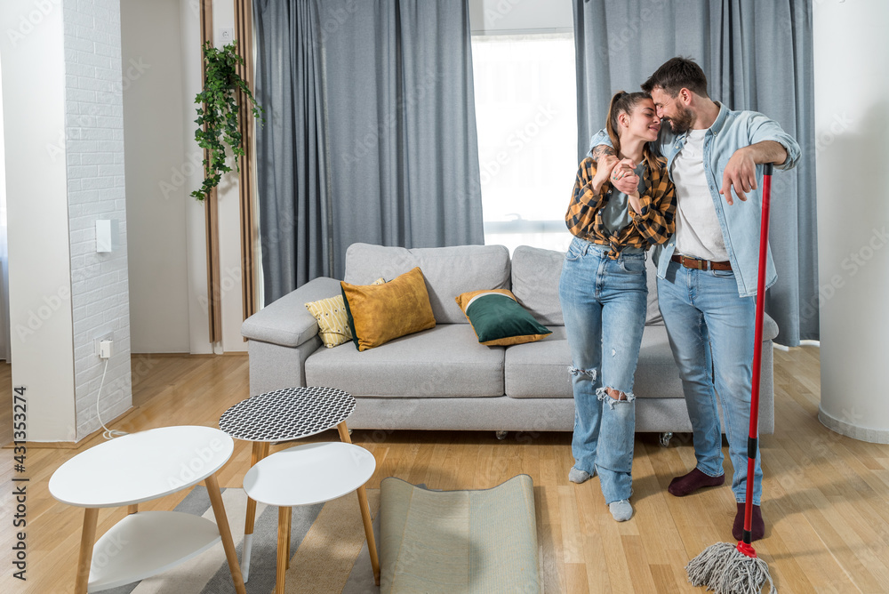 Young happy satisfied couple standing in their apartment with cleaning ...