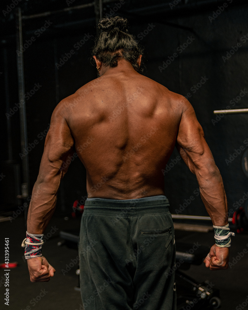Shallow focus of an adult bodybuilder man with long hair showing his ...