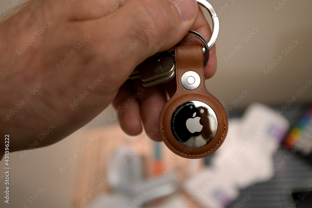 Paris, France - May 2, 2021: Man holding new AirTag in leather key ring ...