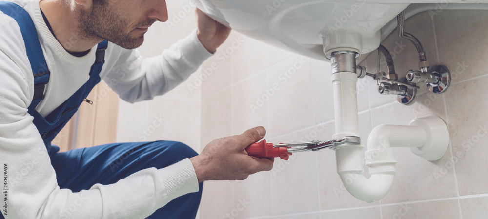 Plumber fixing a sink at home Stock Photo | Adobe Stock