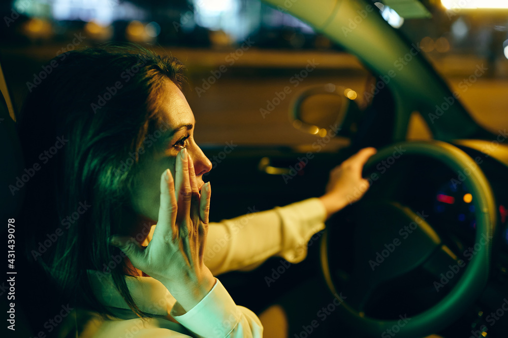 Sad woman wipes away tears while driving a car at night. Stock Photo ...